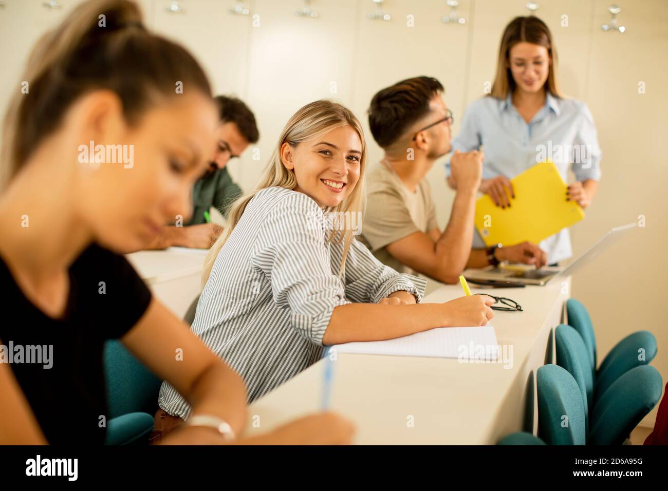Group of university students in the classroom with young female ...