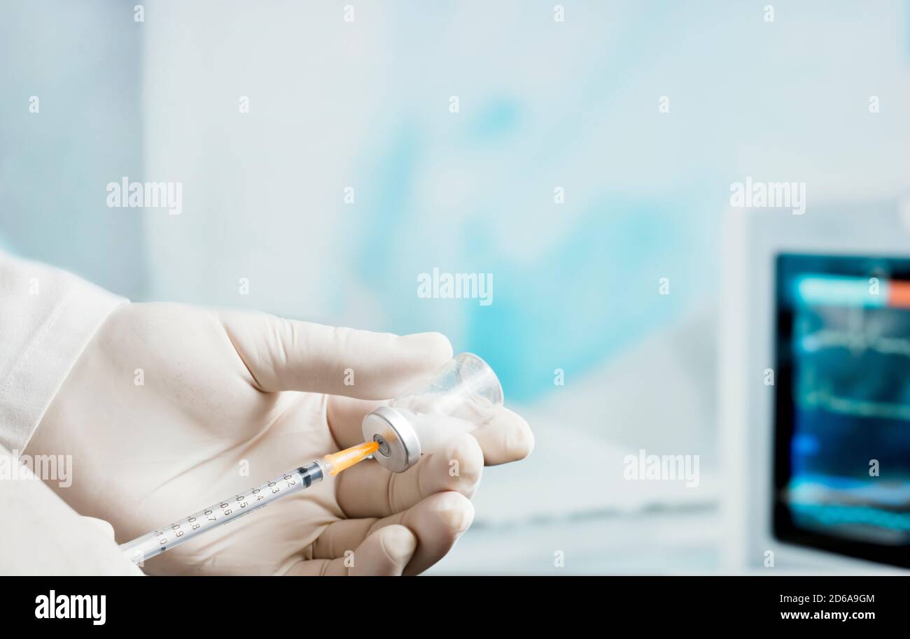 Syringe in the doctor's hand, (focus on orange needle cannula) hospital ...