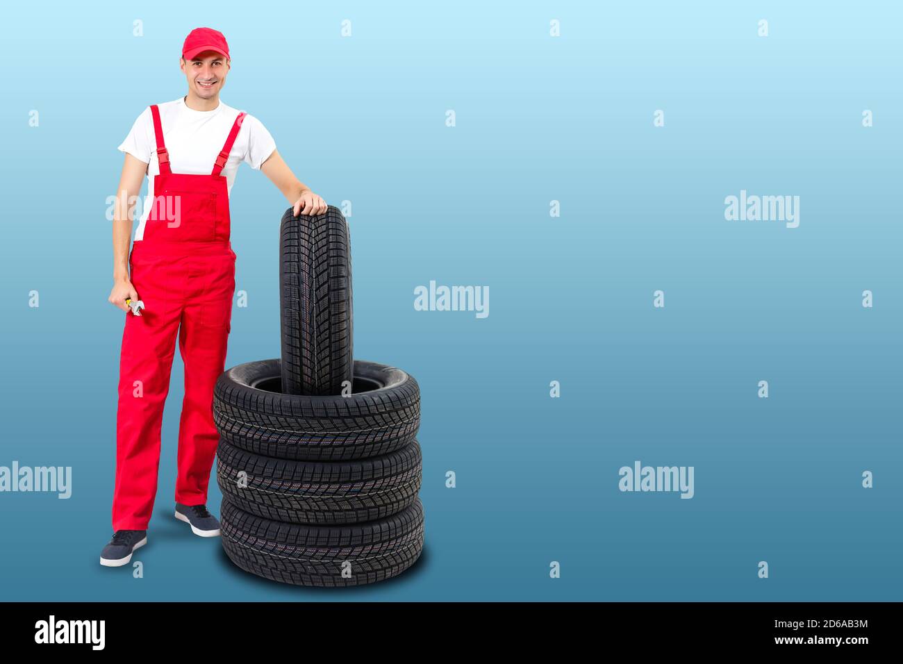 car mechanic carrying tire on blue background. happy man smiling amd ...