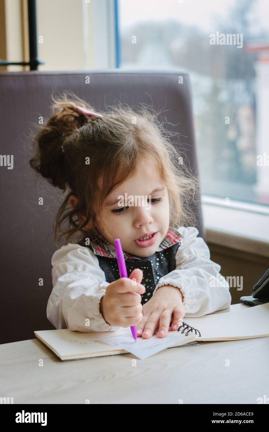 Little kid girl writing or drawing with pen in scetch book Stock Photo ...
