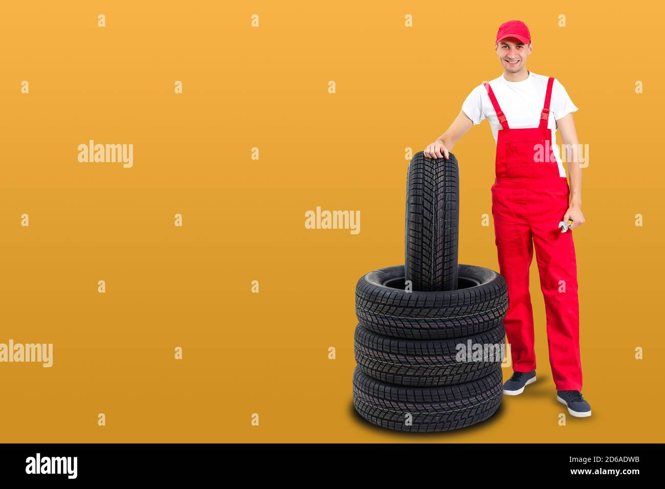 car mechanic carrying tire on yellow background. happy man smiling amd ...