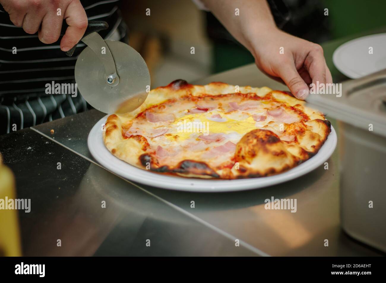 Chef cutting pizza with the round pizza knife Stock Photo - Alamy