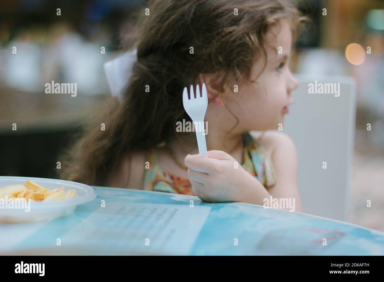 Little girl with the plastic fork in hands at cafe or restaurant Stock ...