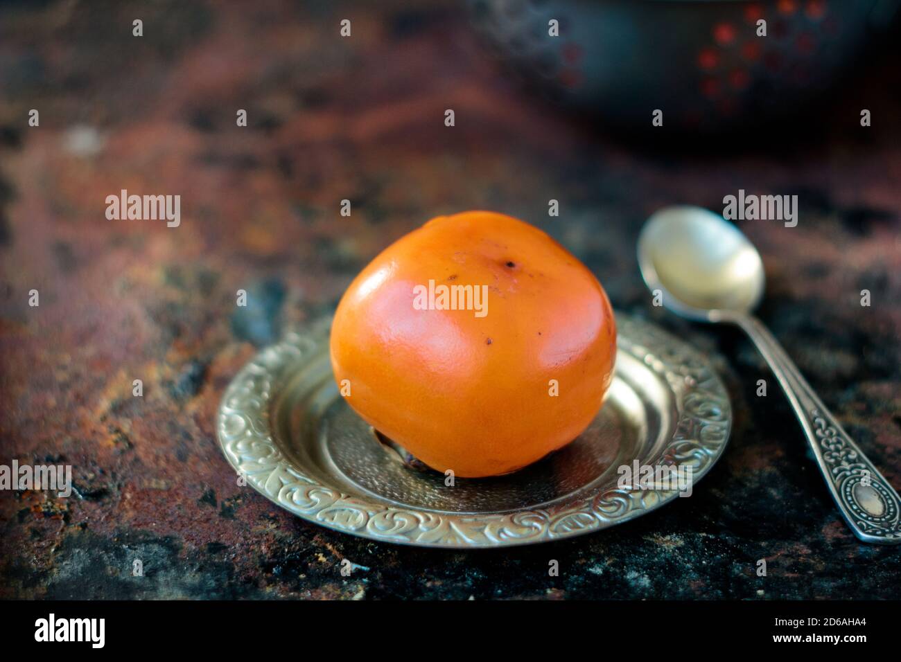 Ripe persimmon on metal plate over black rustic surface Stock Photo - Alamy