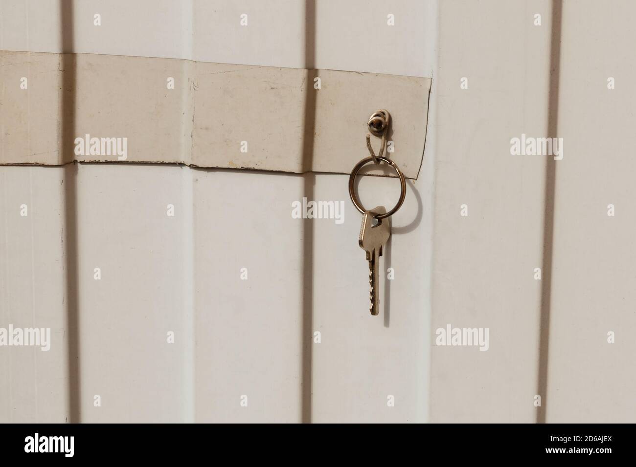 The key is hanging from a hook on a metal fence. The key to the door ...