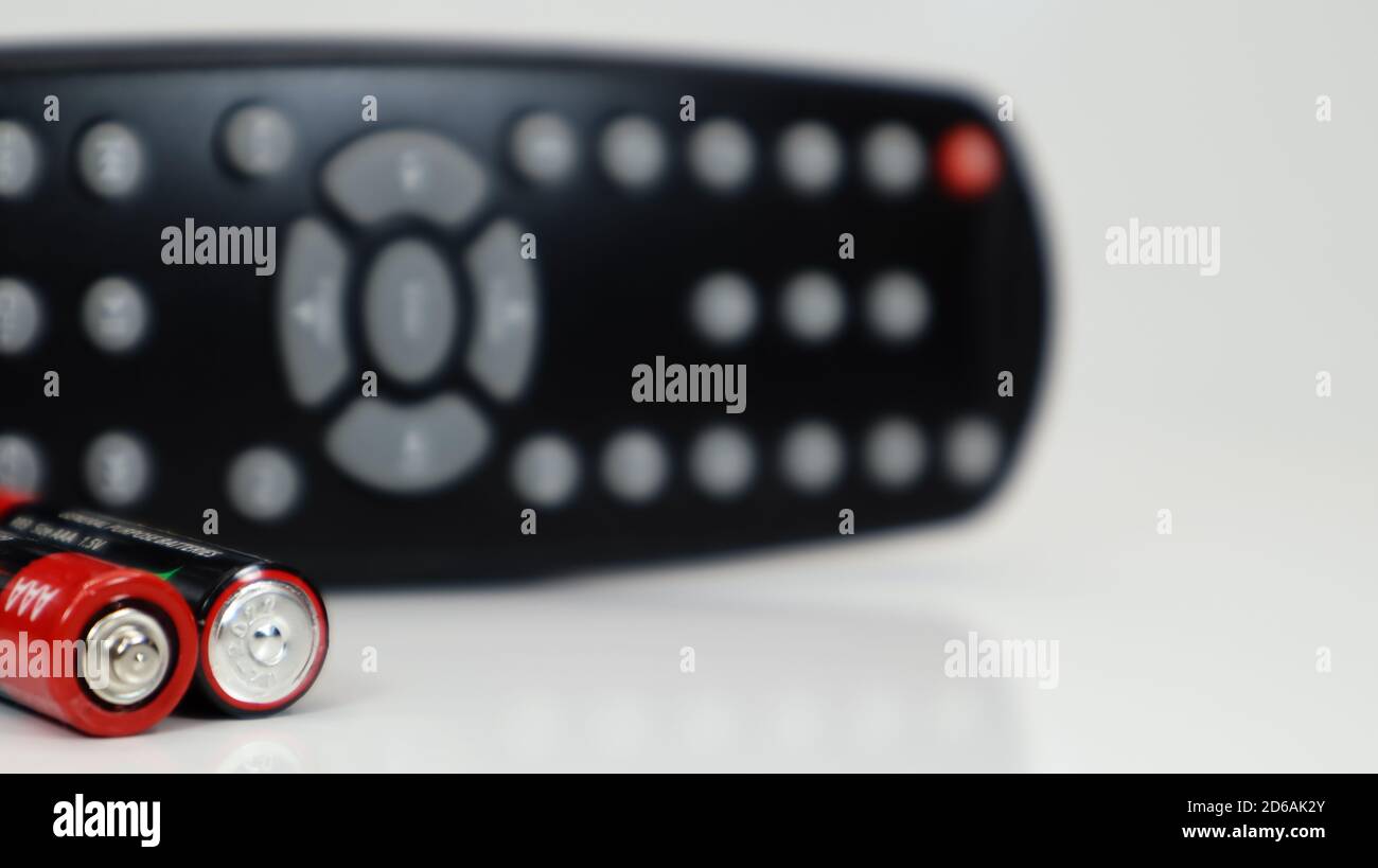 Black TV remote control with AAA alkaline batteries in red and white on ...