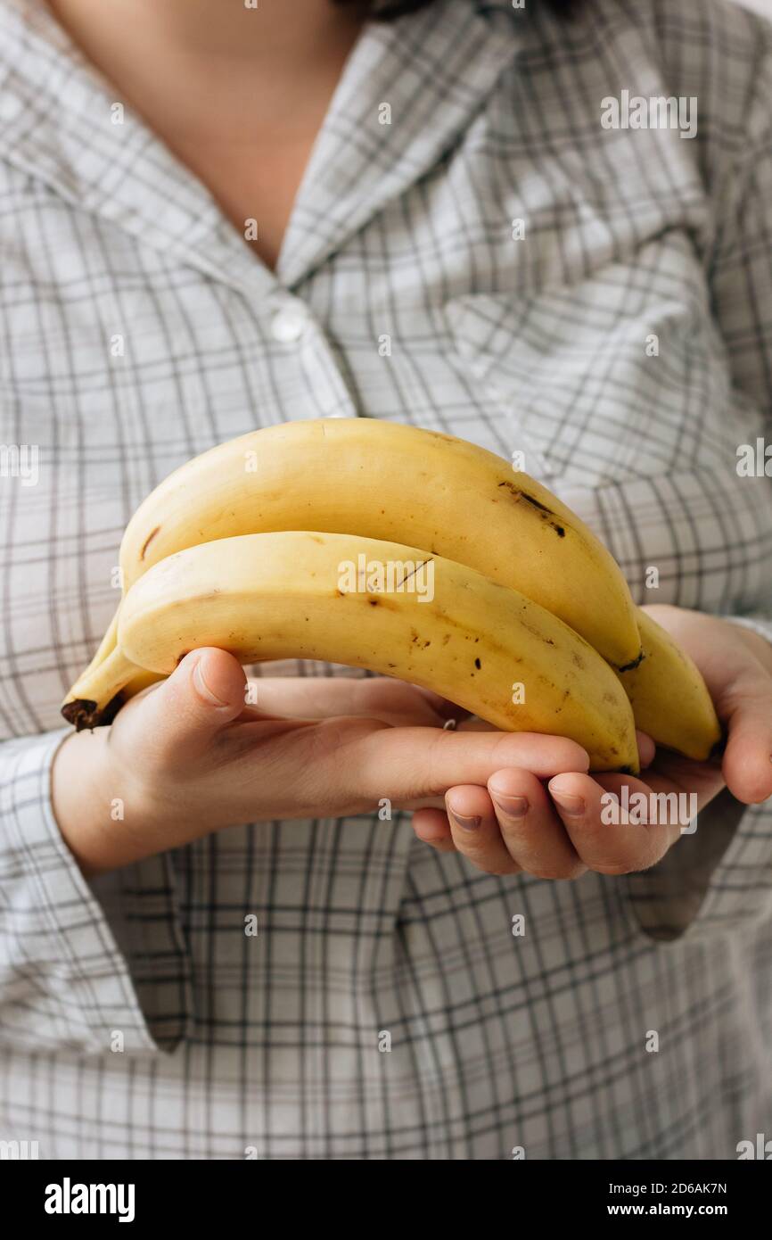 Woman holding three ripe bananas in arms Stock Photo - Alamy
