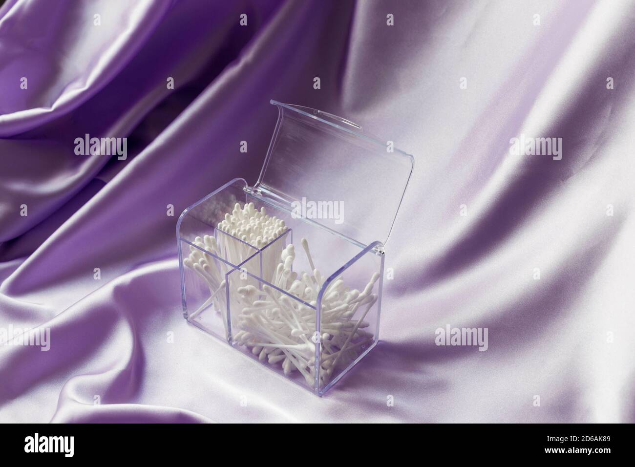 ear sticks in a transparent container on a purple silk cloth with soft ...