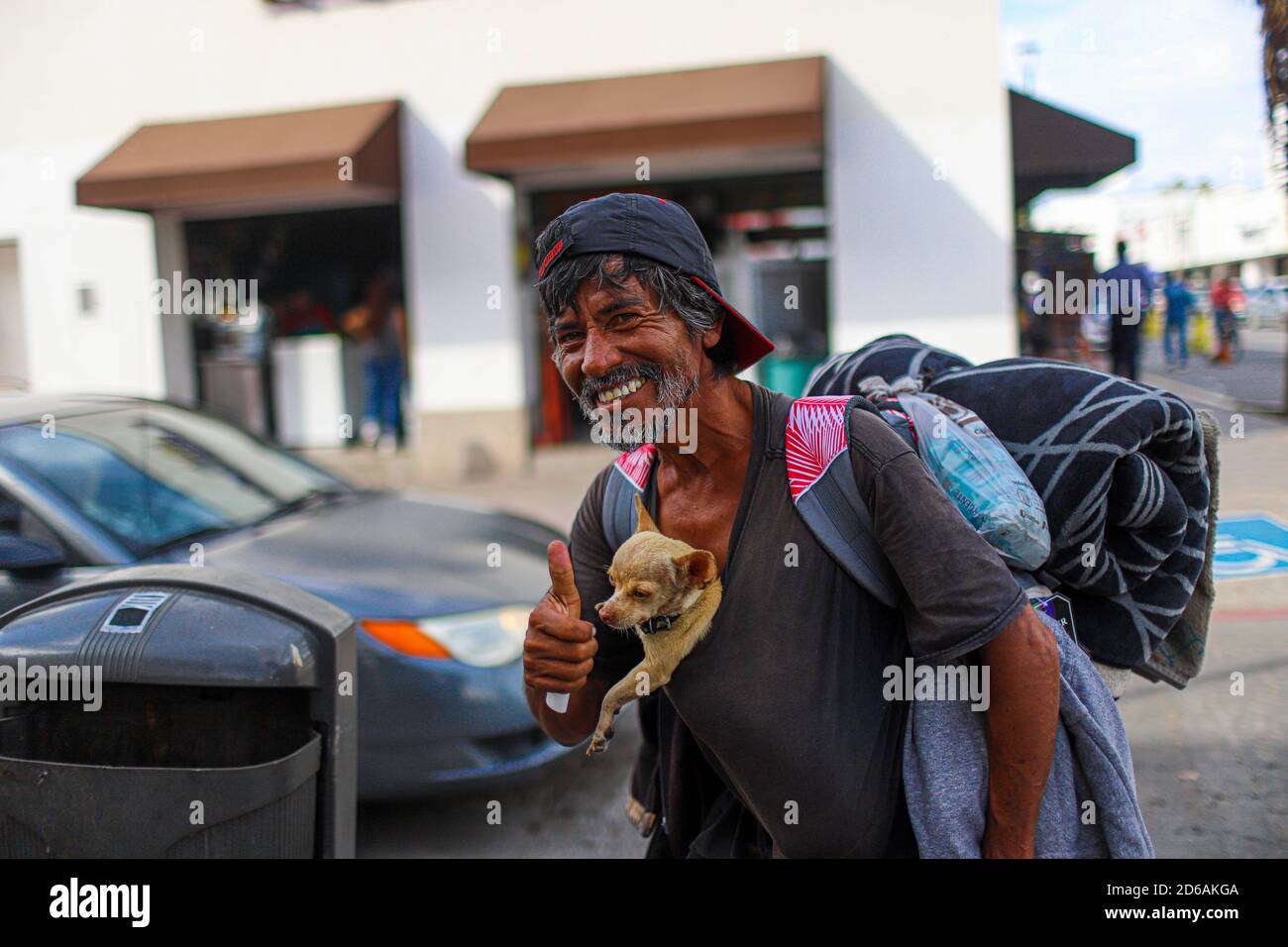 A destitute or extremely poor man smiles as he walks with his Chihuahua ...