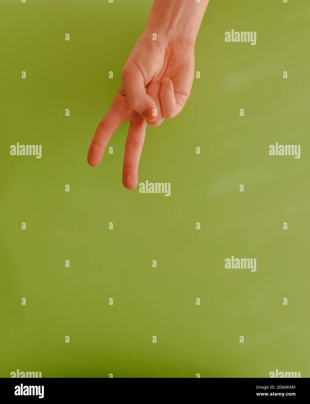 Man doing the peace sign with his hand on an isolated green background ...
