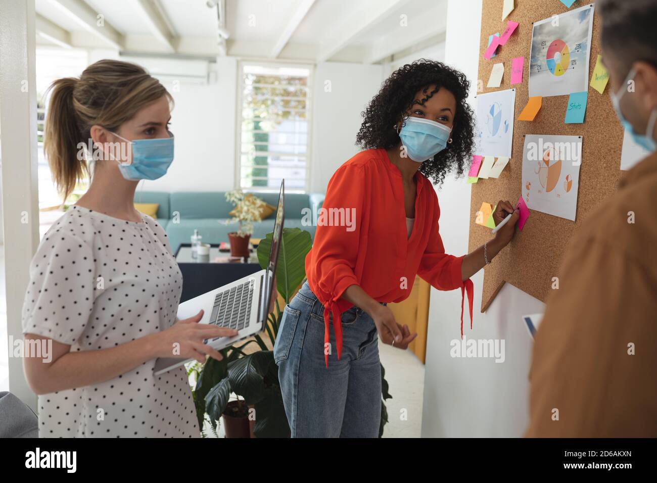 Office colleagues wearing face mask discussing over memo notes at ...