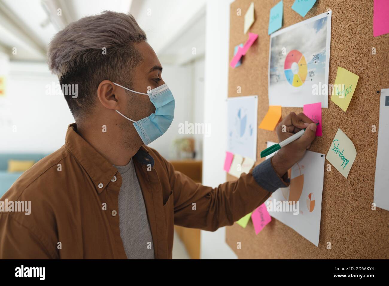 Man wearing face mask writing on memo notes at office Stock Photo - Alamy