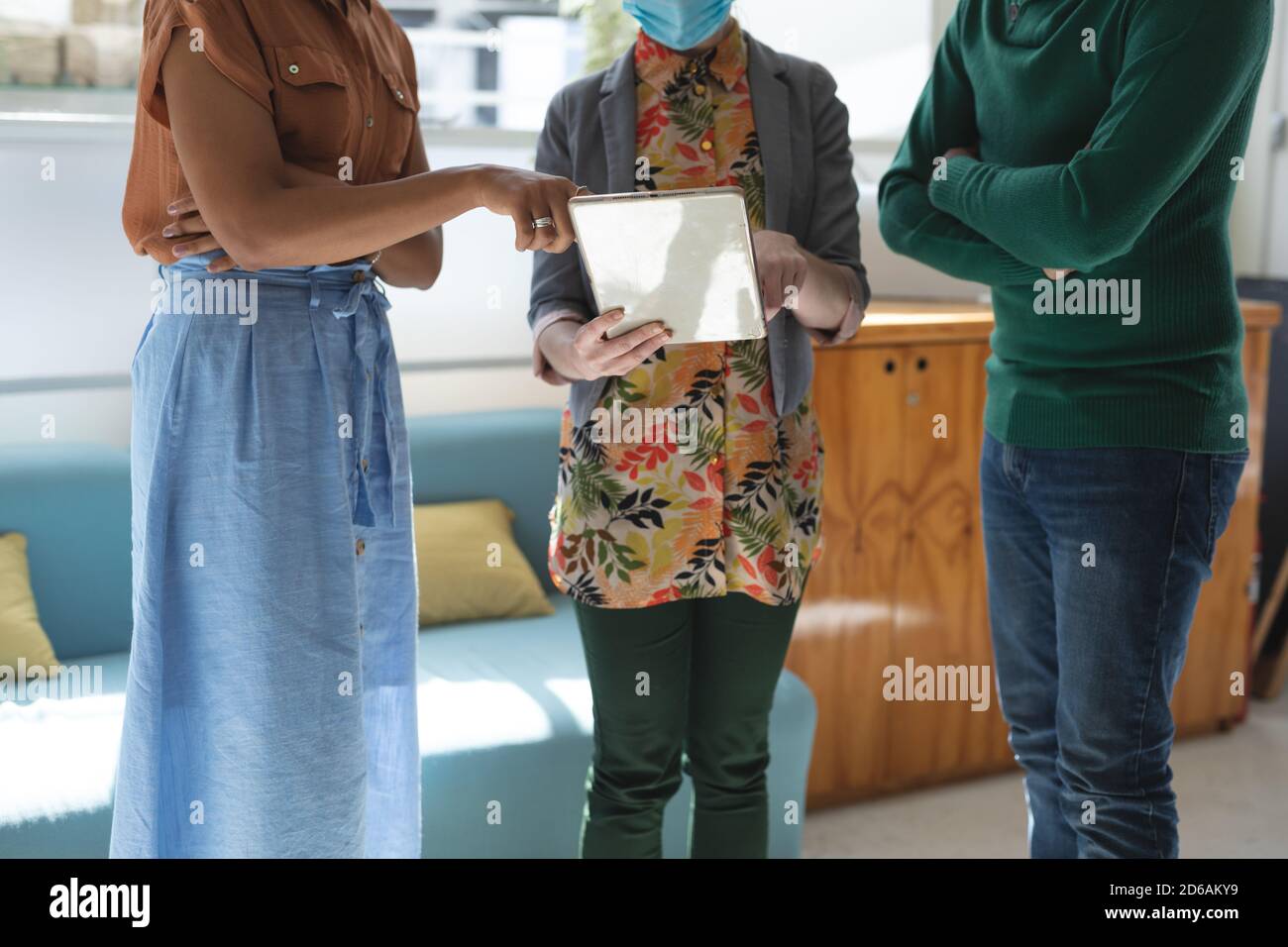 Mid section of office colleagues wearing face mask discussing over ...
