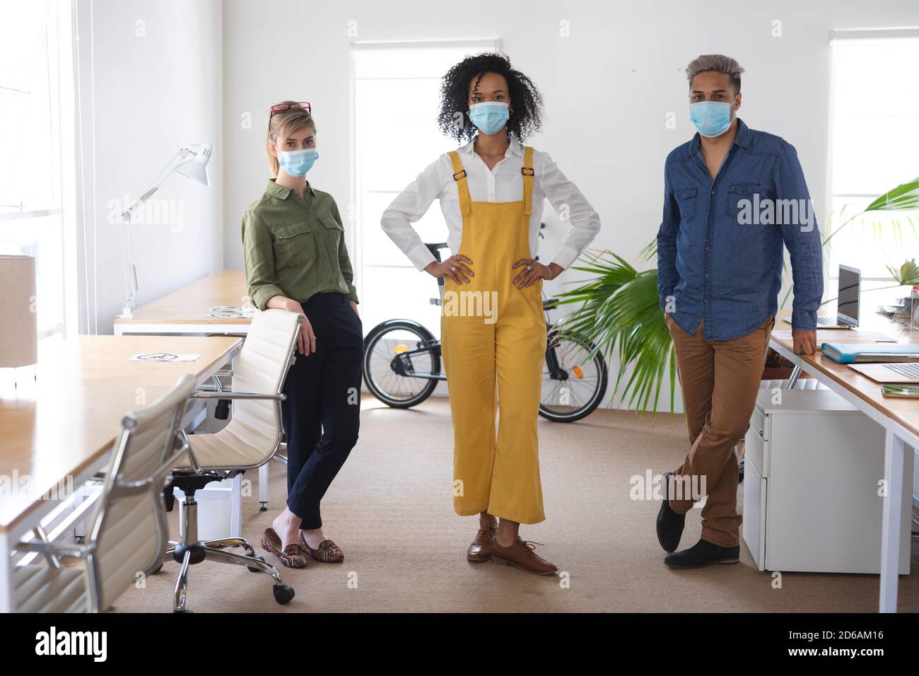 Portrait of office colleagues wearing face mask standing in office ...