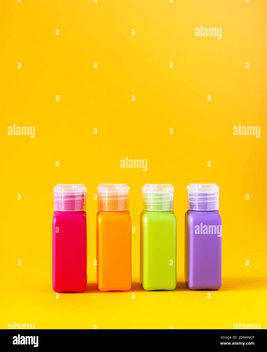 Colorful plastic bottles for skincare products on bright yellow ...