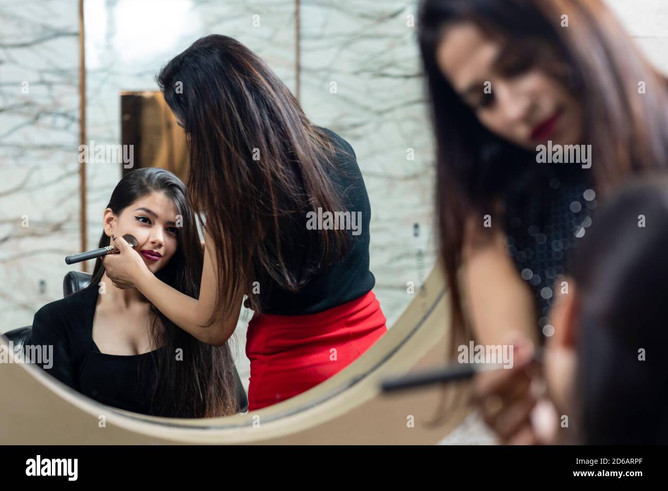A young Indian model at a beauty salon, artist doing makeup for a ...