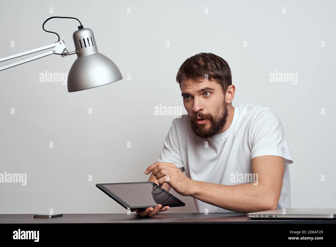 A man with a tablet at the table gestures with his hands on a light ...