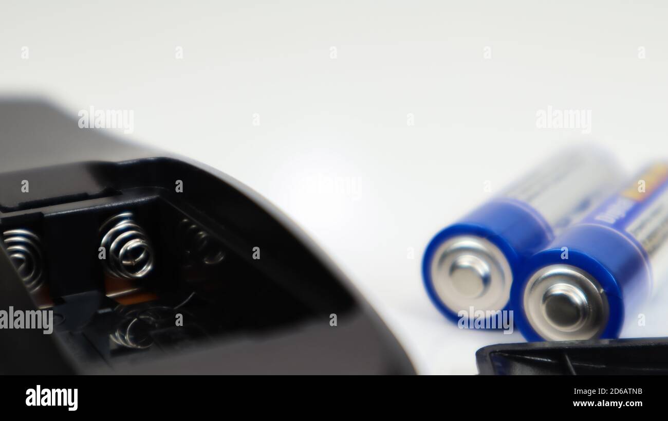 Black remote control with blue AAA batteries on a white background ...