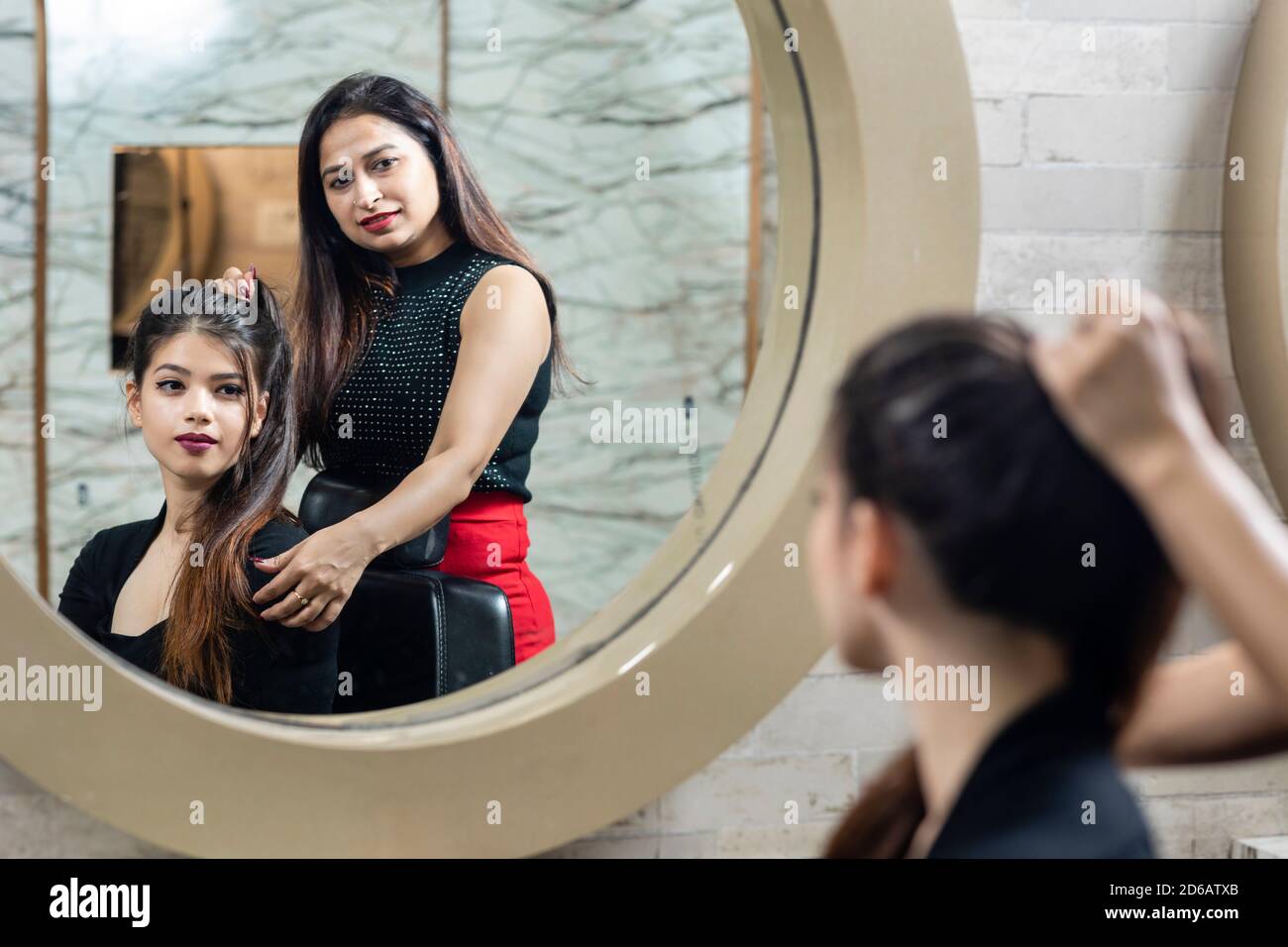 Portrait of a female hairdresser standing and making hairstyle of a ...