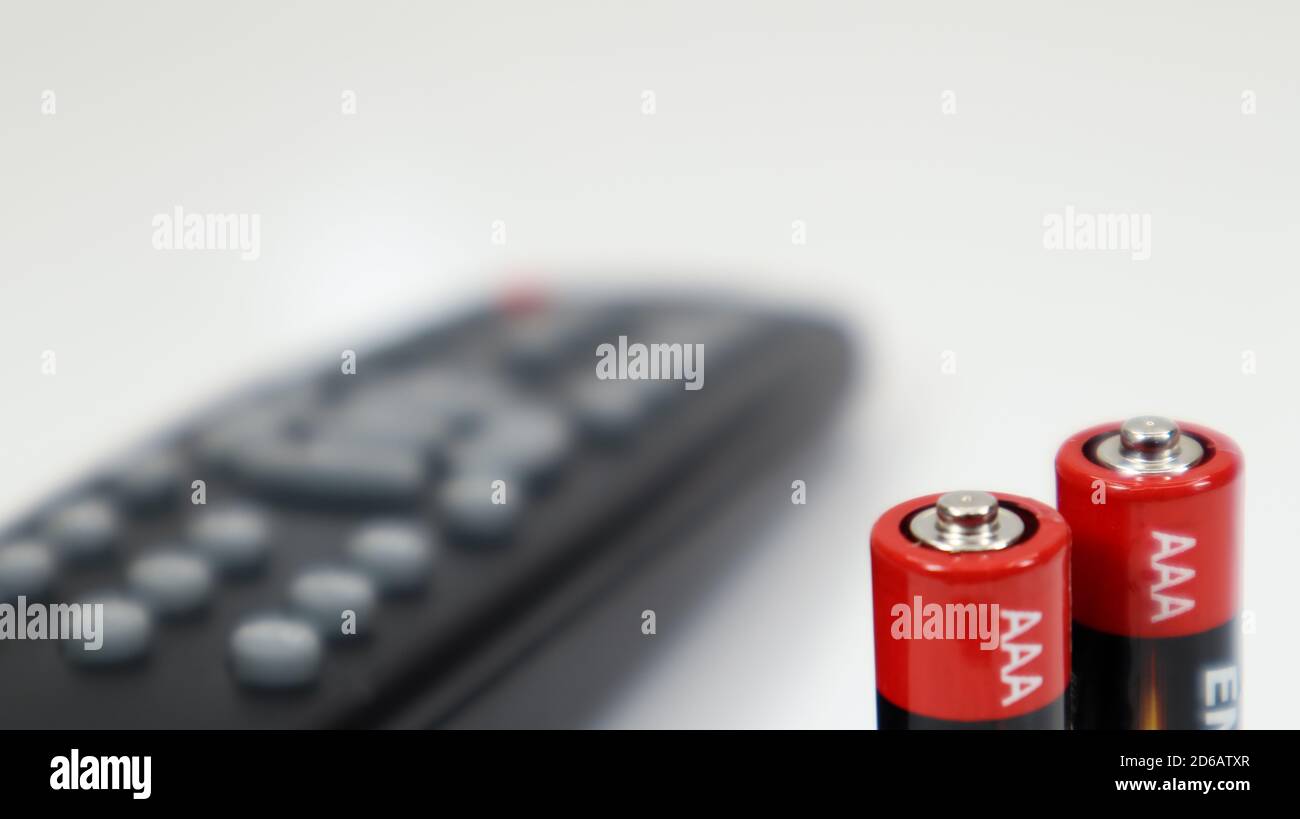 Black TV remote control with AAA alkaline batteries in red and white on ...