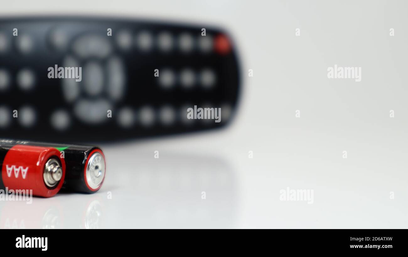 Black TV remote control with AAA alkaline batteries in red and white on ...