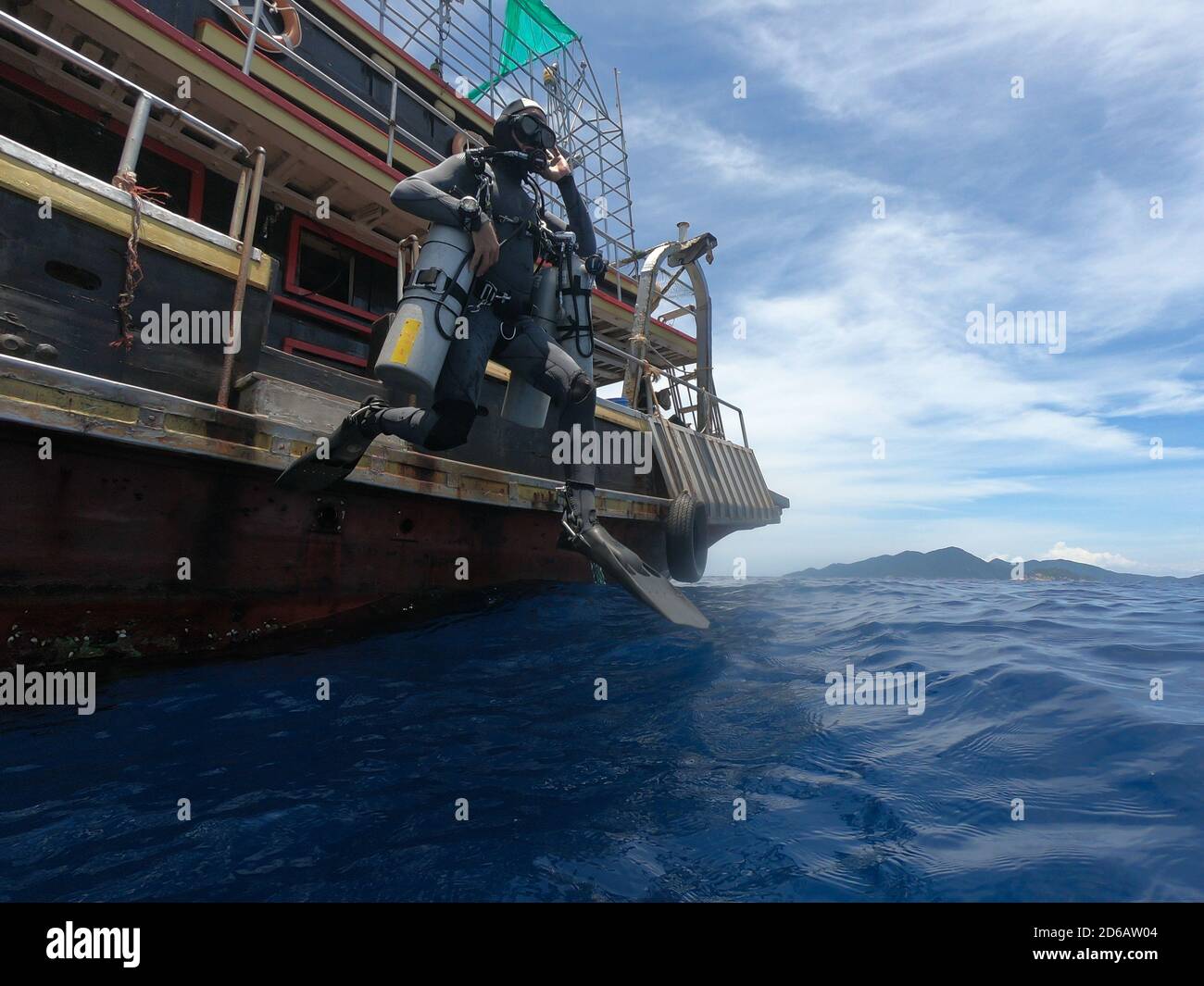 Scuba diver jumping into blue water from a boat Stock Photo - Alamy