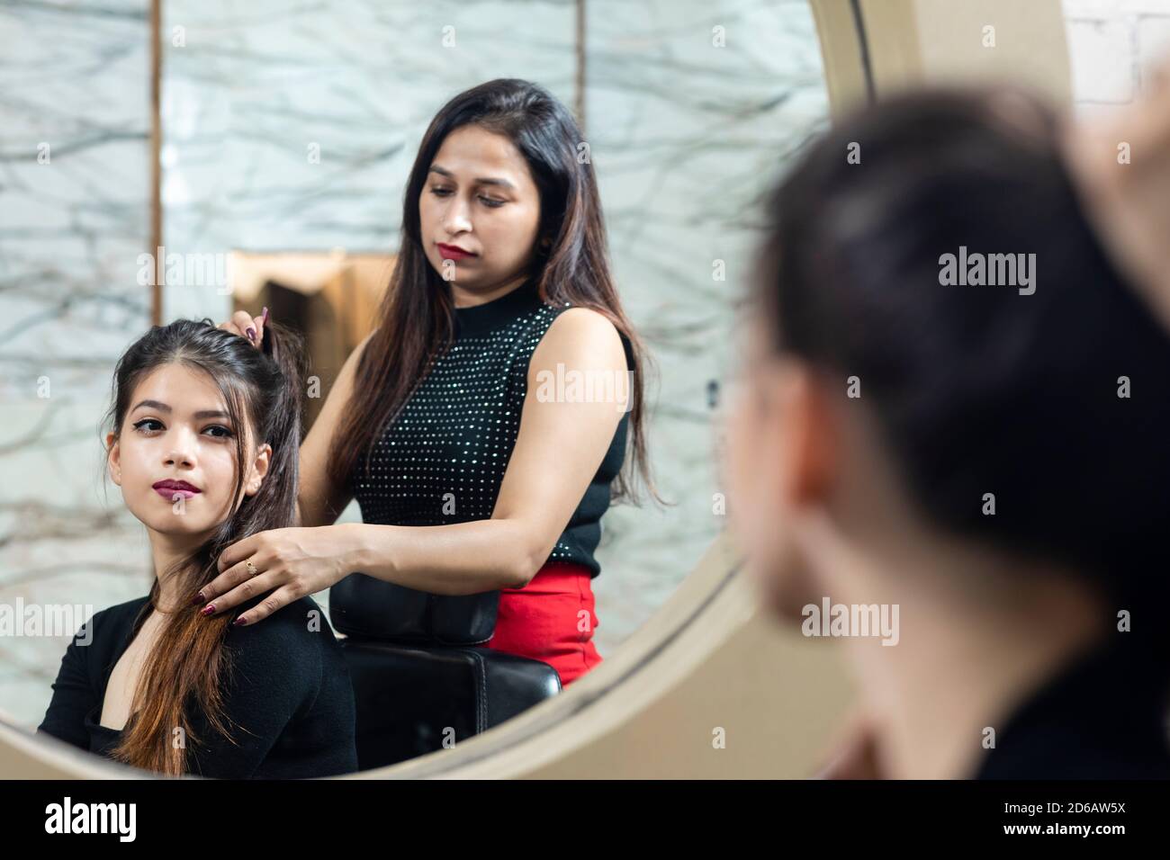 Portrait of a female hairdresser standing and making hairstyle of a ...