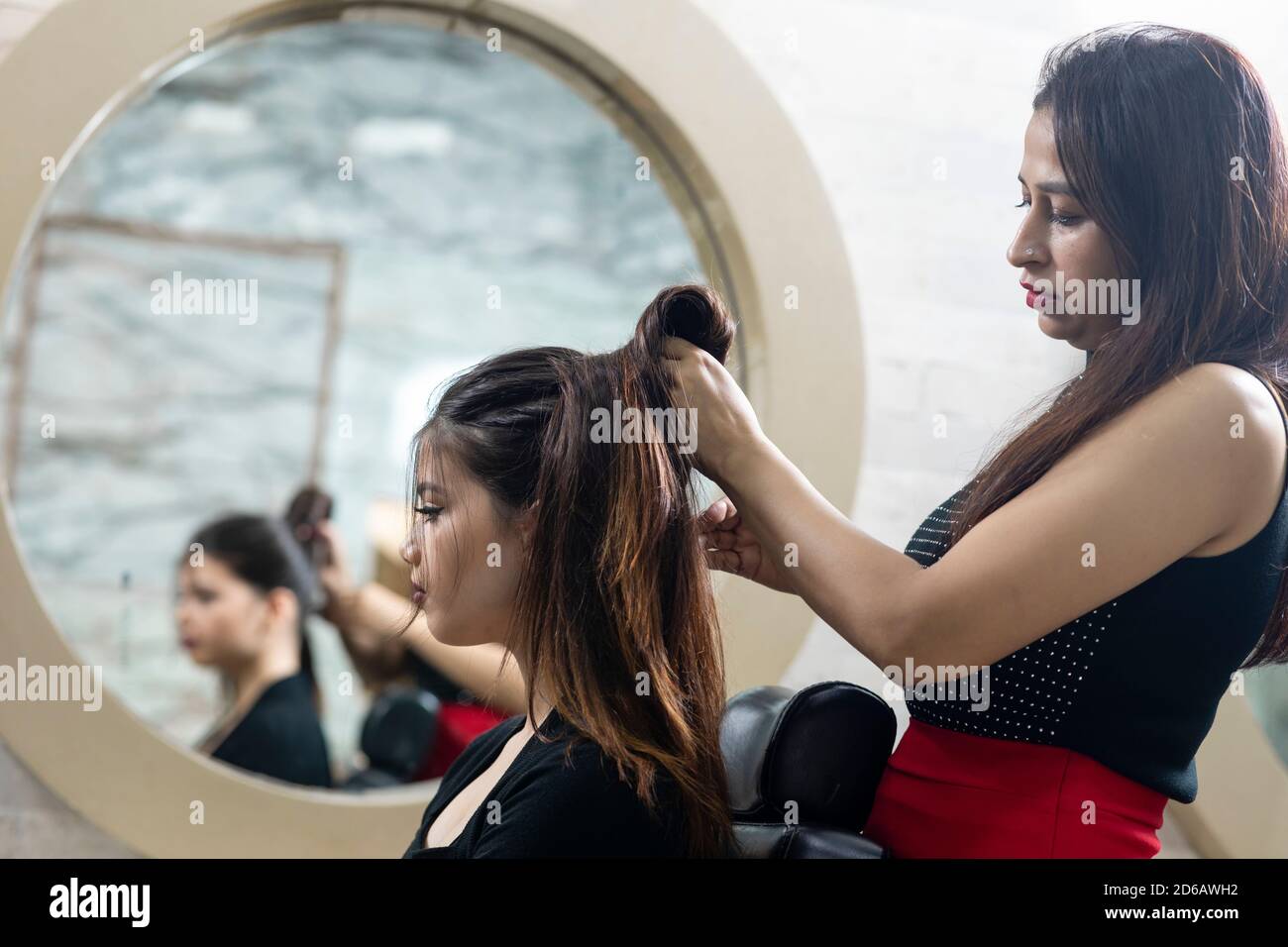 Portrait of a female hairdresser standing and making hairstyle of a ...