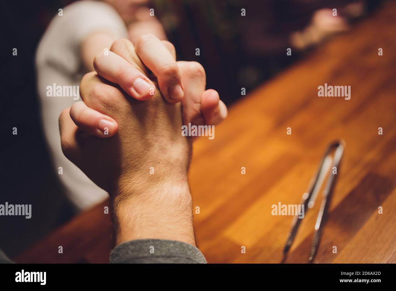 Close up male and female holding hands over table Stock Photo - Alamy