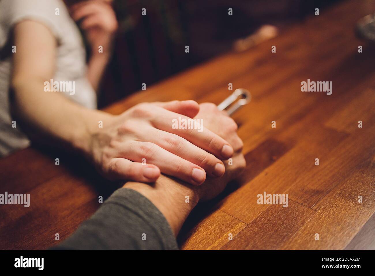 Close up male and female holding hands over table Stock Photo - Alamy