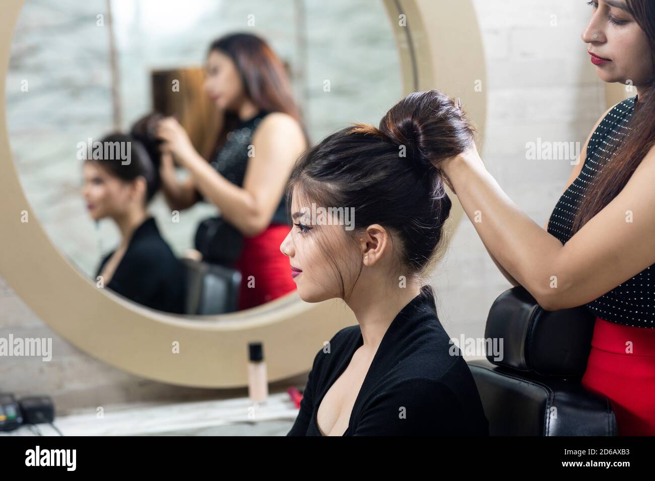 Portrait of a female hairdresser standing and making hairstyle of a ...