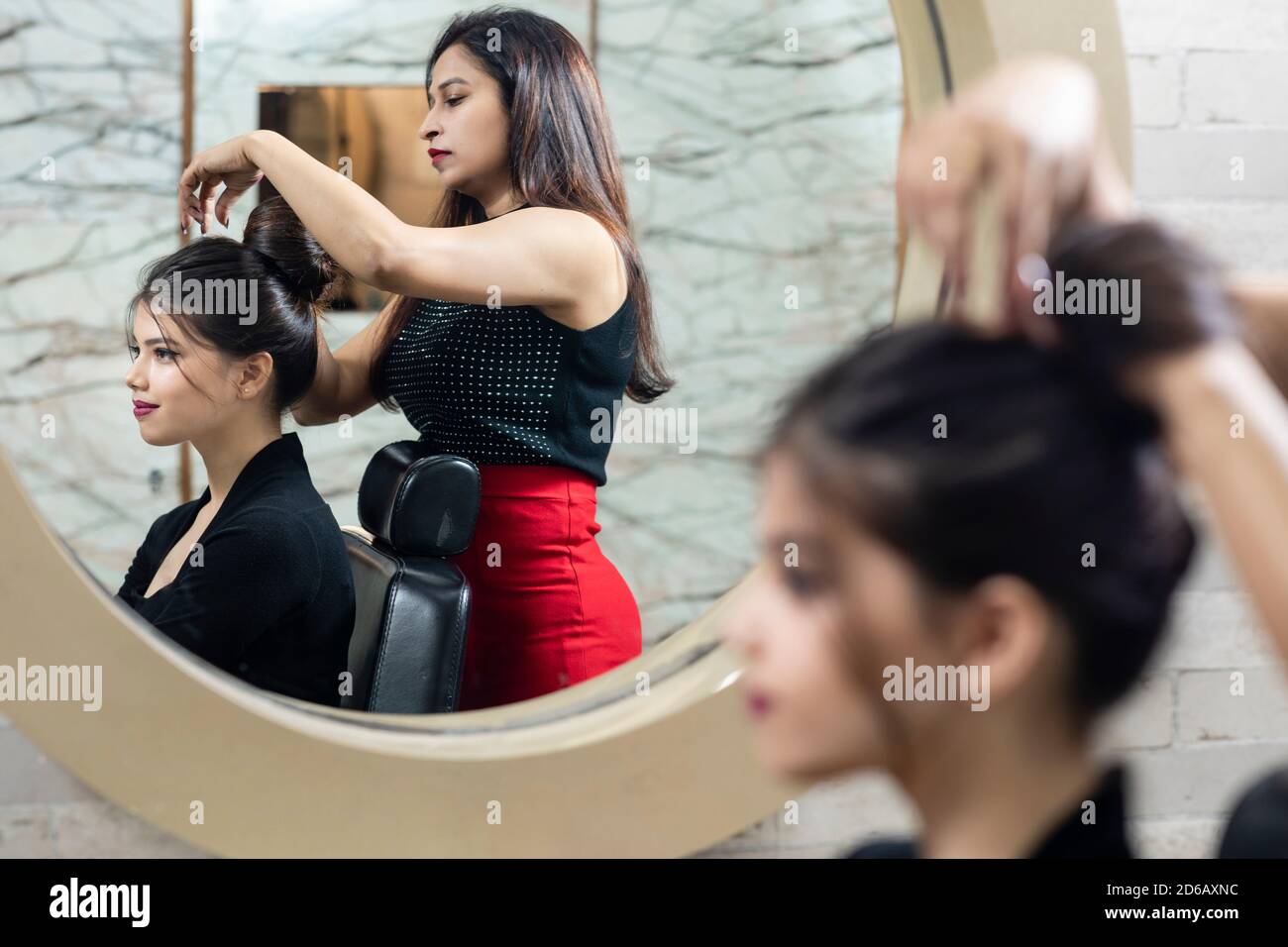 Portrait of a female hairdresser standing and making hairstyle of a ...