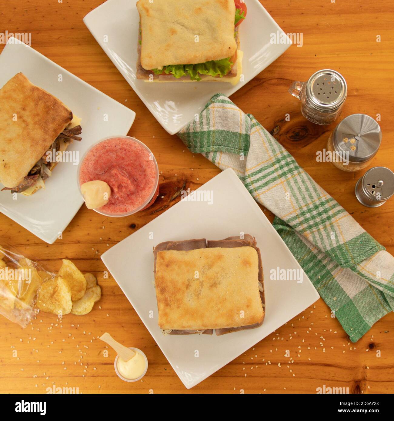Top view of ham sandwiches on plates on the table with chips on it ...