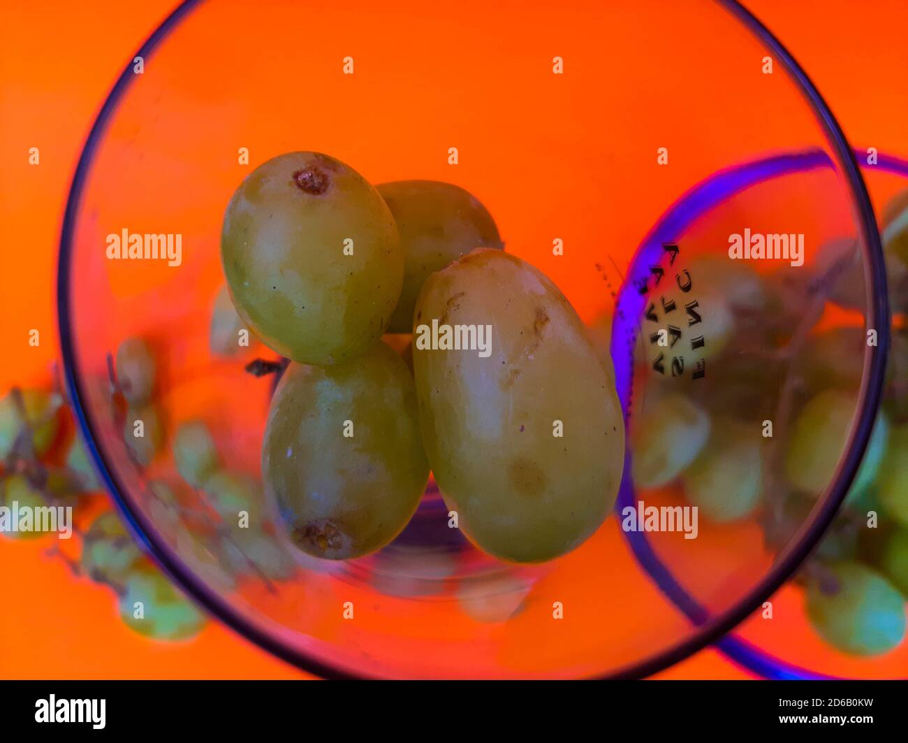 Closeup of green grapes in a transparent container on the orange ...