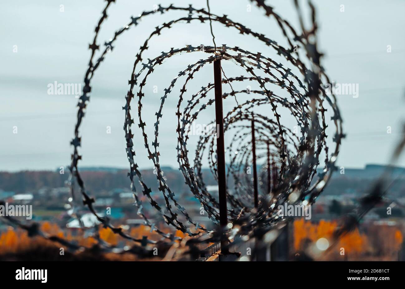 Security with a barbed wire spiral wound on the fence on a cloudy day ...