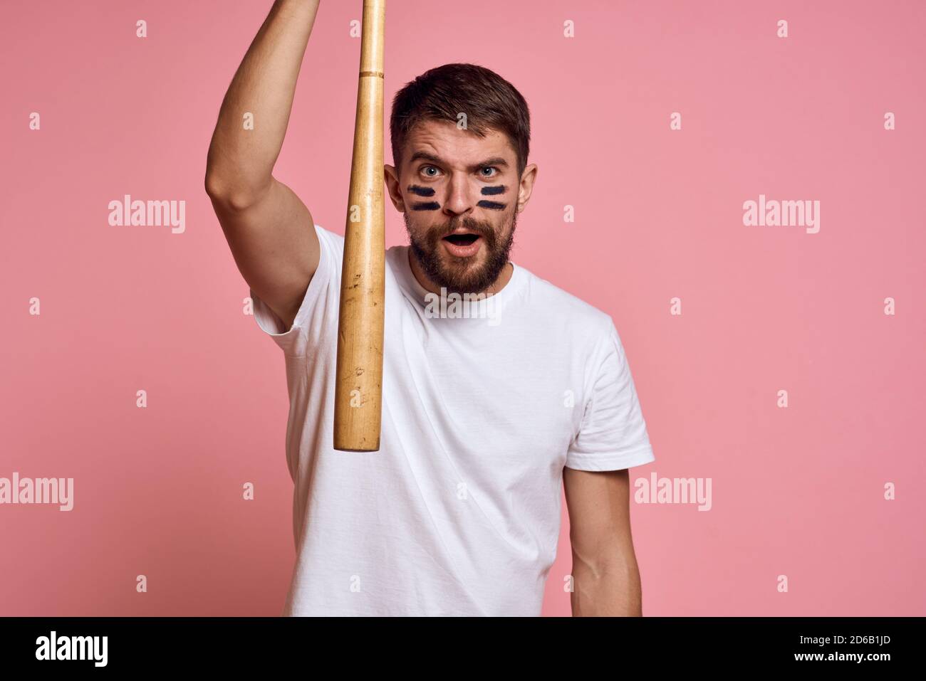 Emotional man with a baseball bat in his hand on a pink background and ...