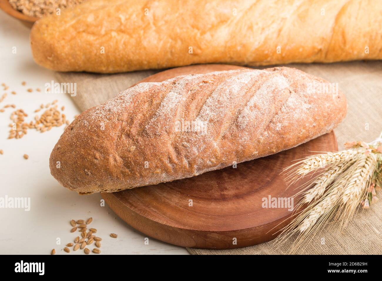 Different kinds of fresh baked bread on a white wooden background. side ...