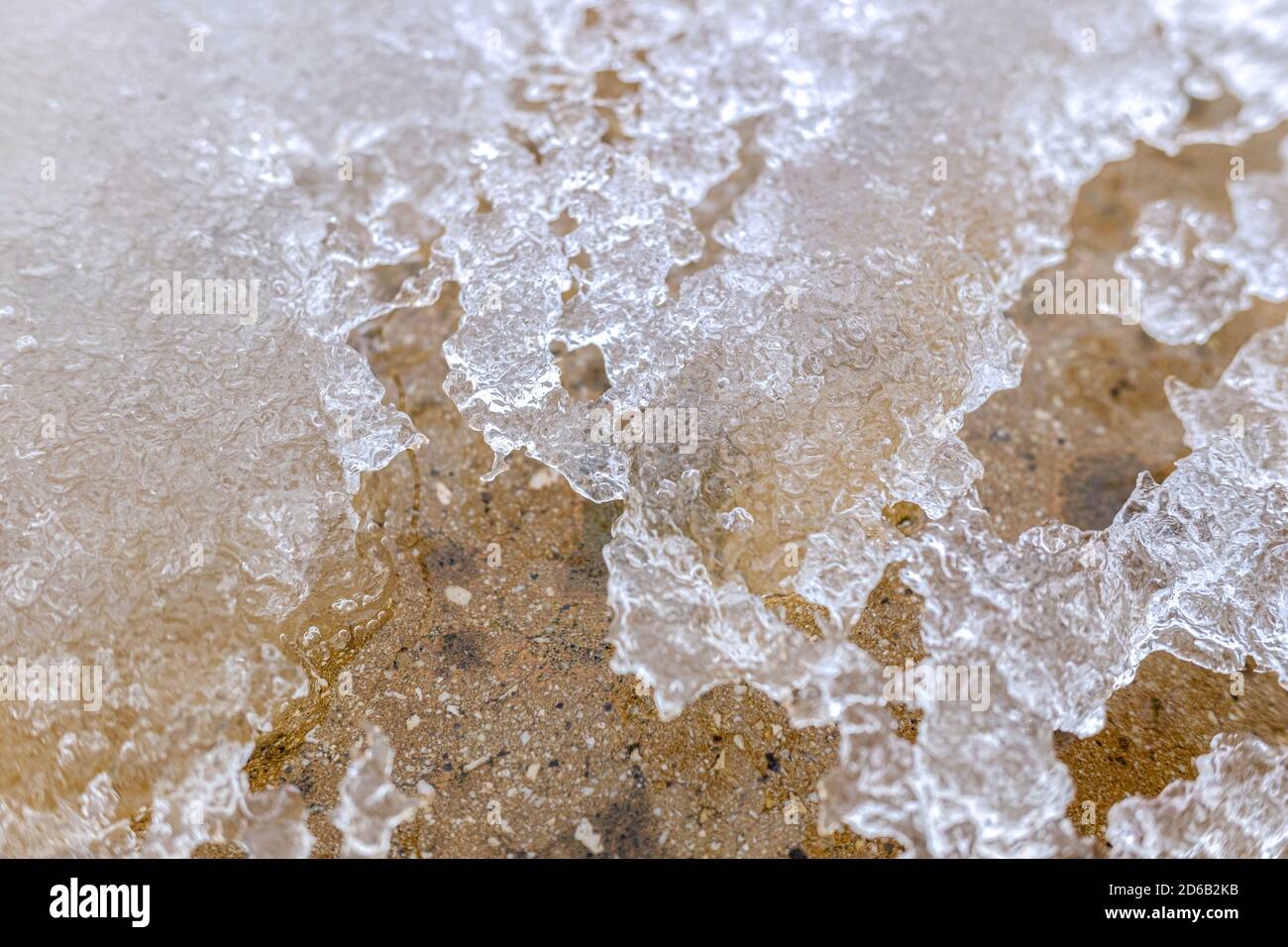 Detail of a thin layer of ice melting on the ground, winter background ...
