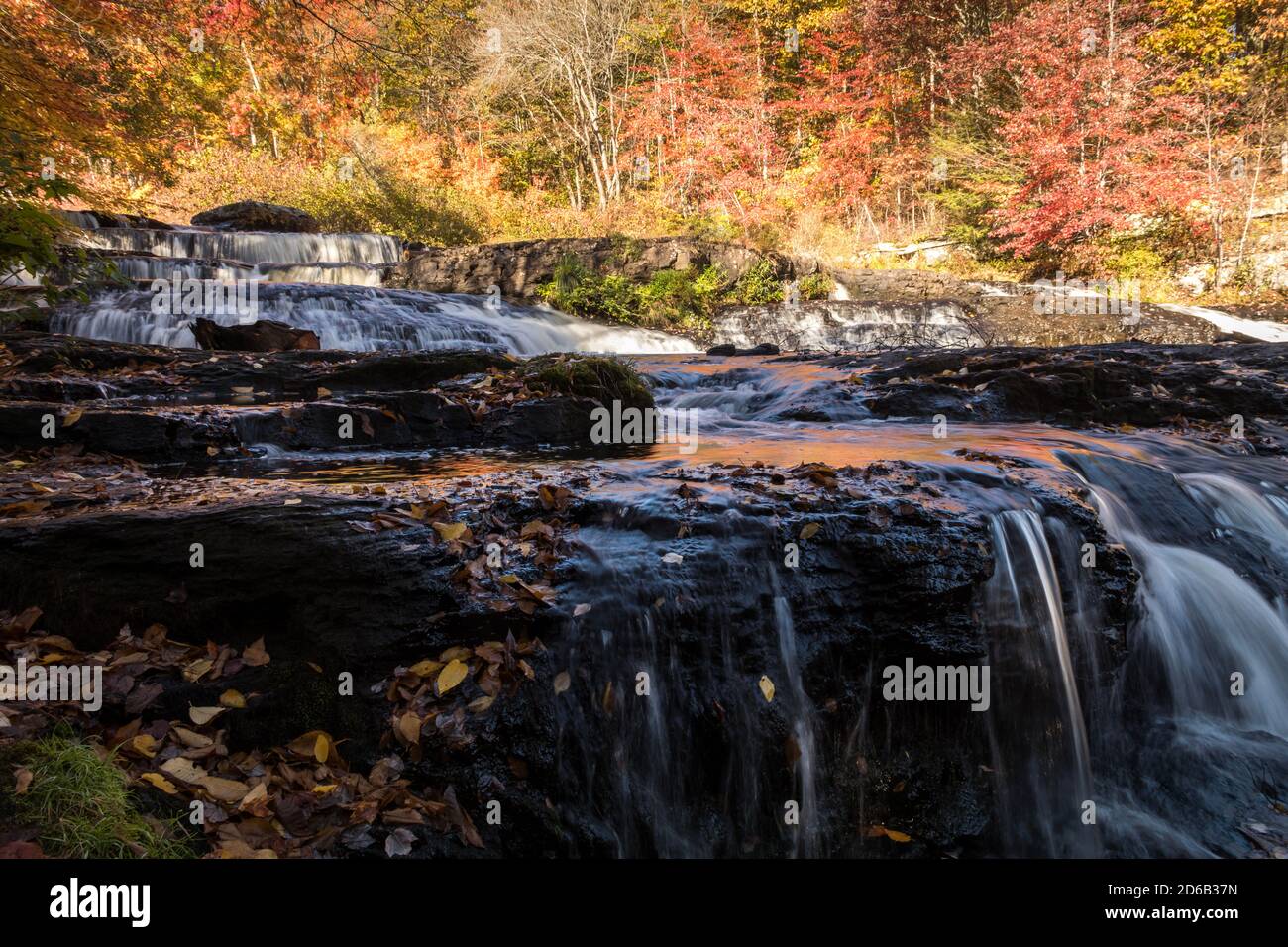 Peak fall foliage surrounds beautiful cascading Shohola Falls on an ...