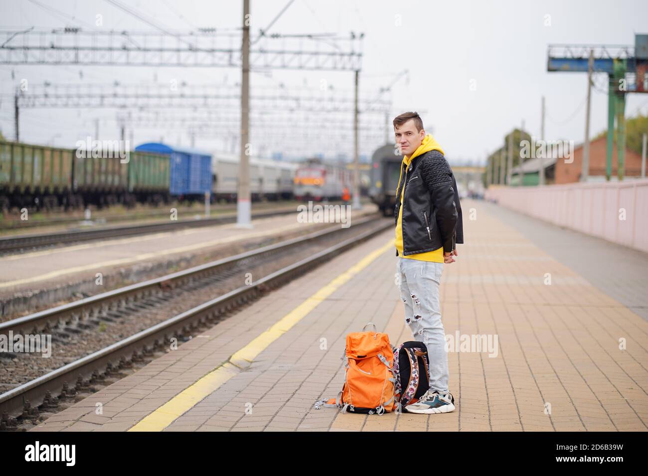 Young man stands on platform, waiting for train. Male passenger with ...