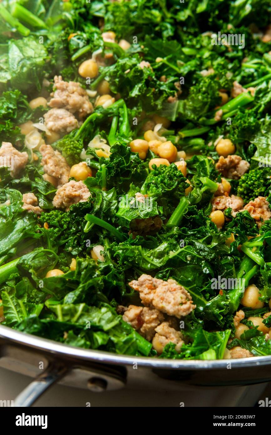 Cooking Italian spicy sausage and broccoli rabe in pot on kitchen stove ...