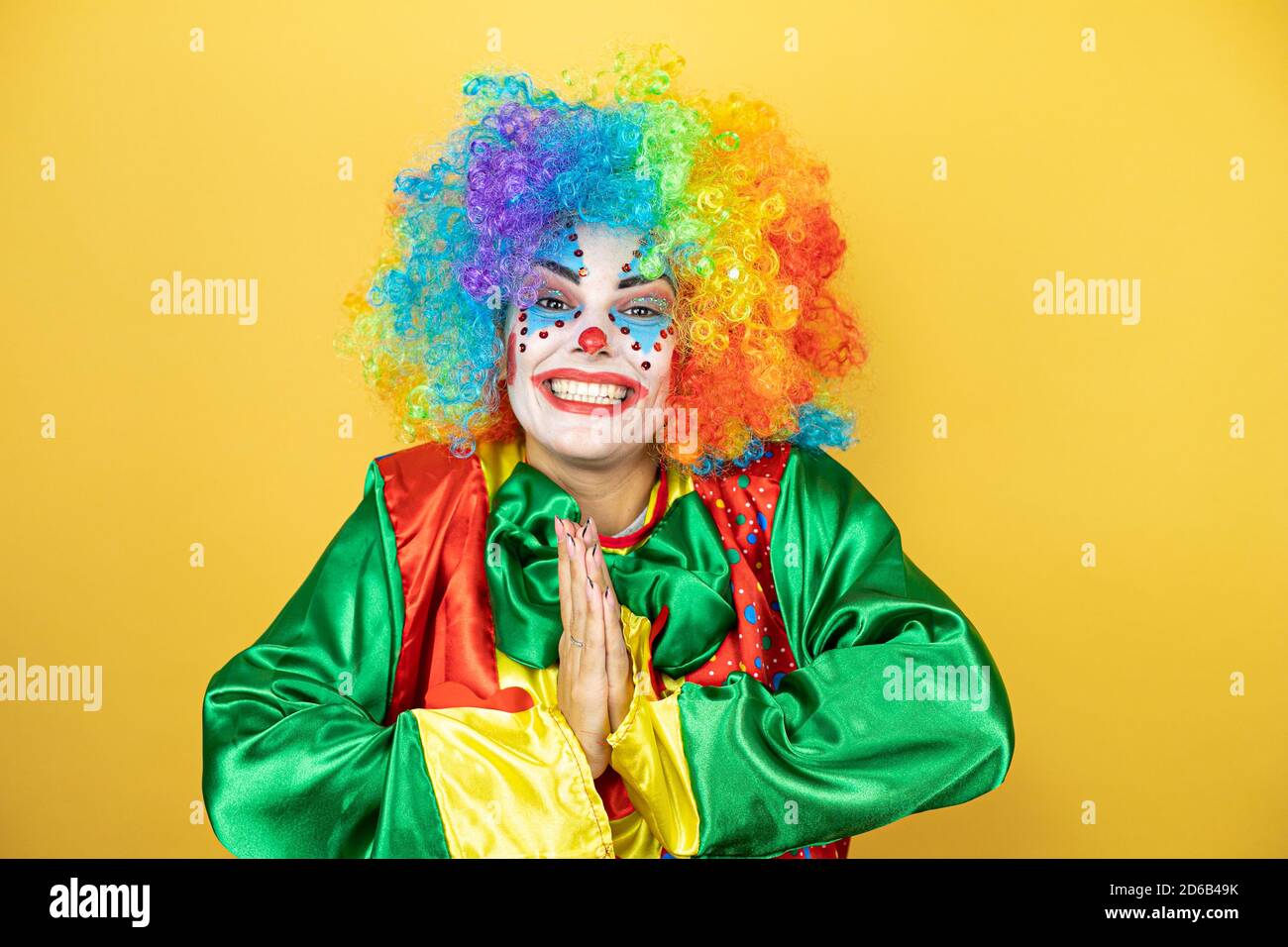 Clown standing over yellow insolated yellow background begging and ...
