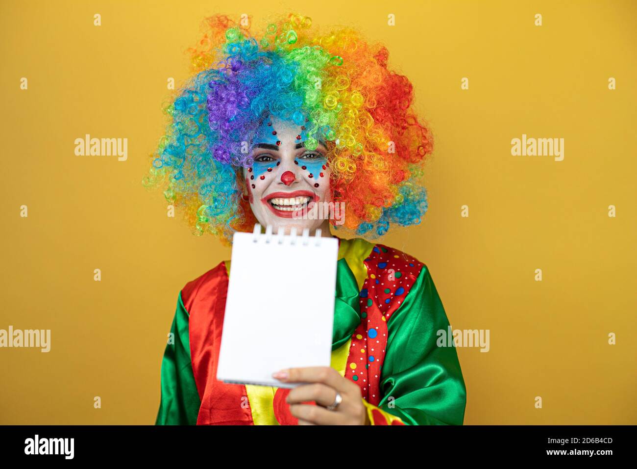 Clown standing over yellow insolated yellow background smiling and ...