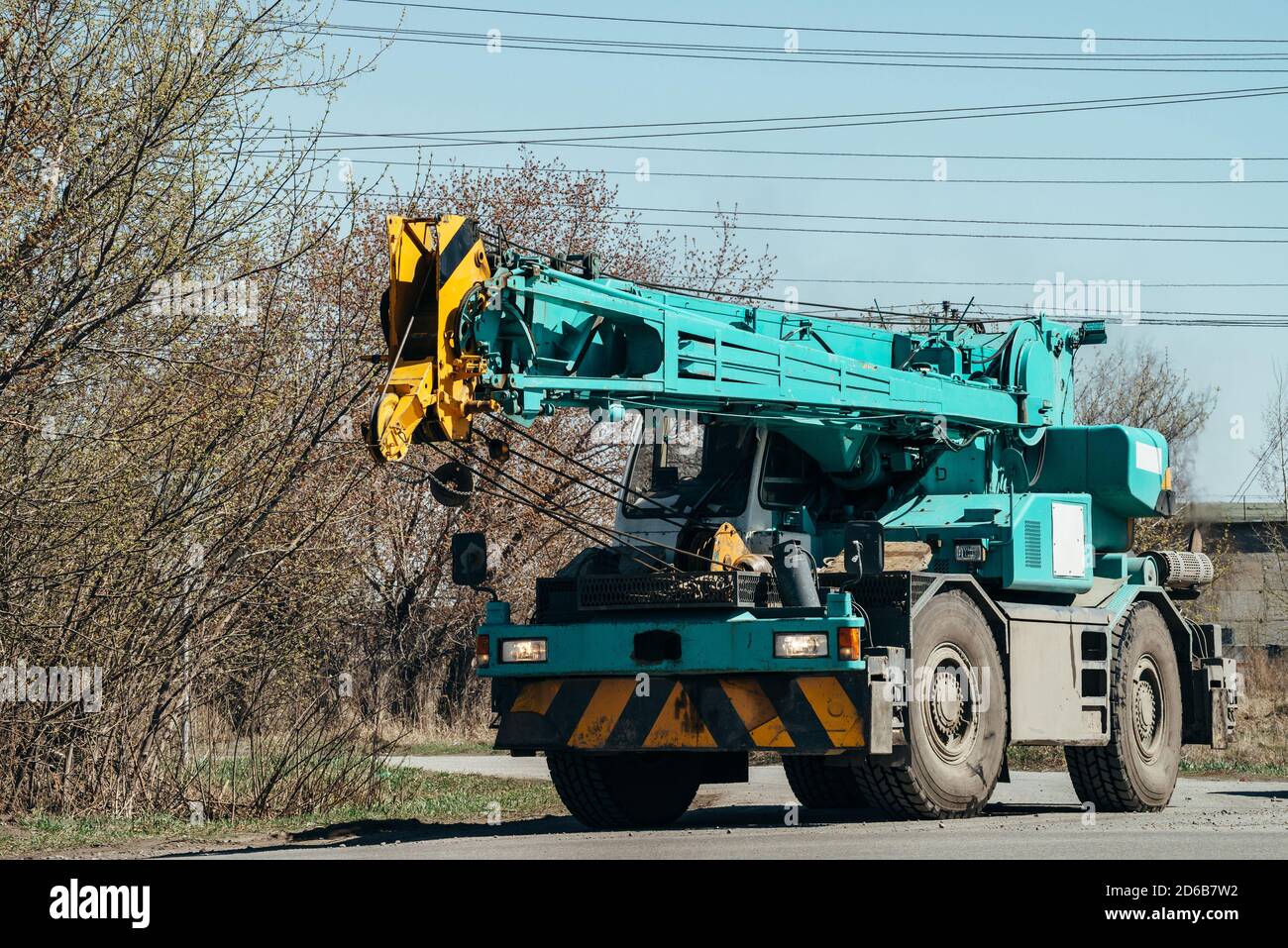 Large heavy car with crane is driving along road under wires Stock ...
