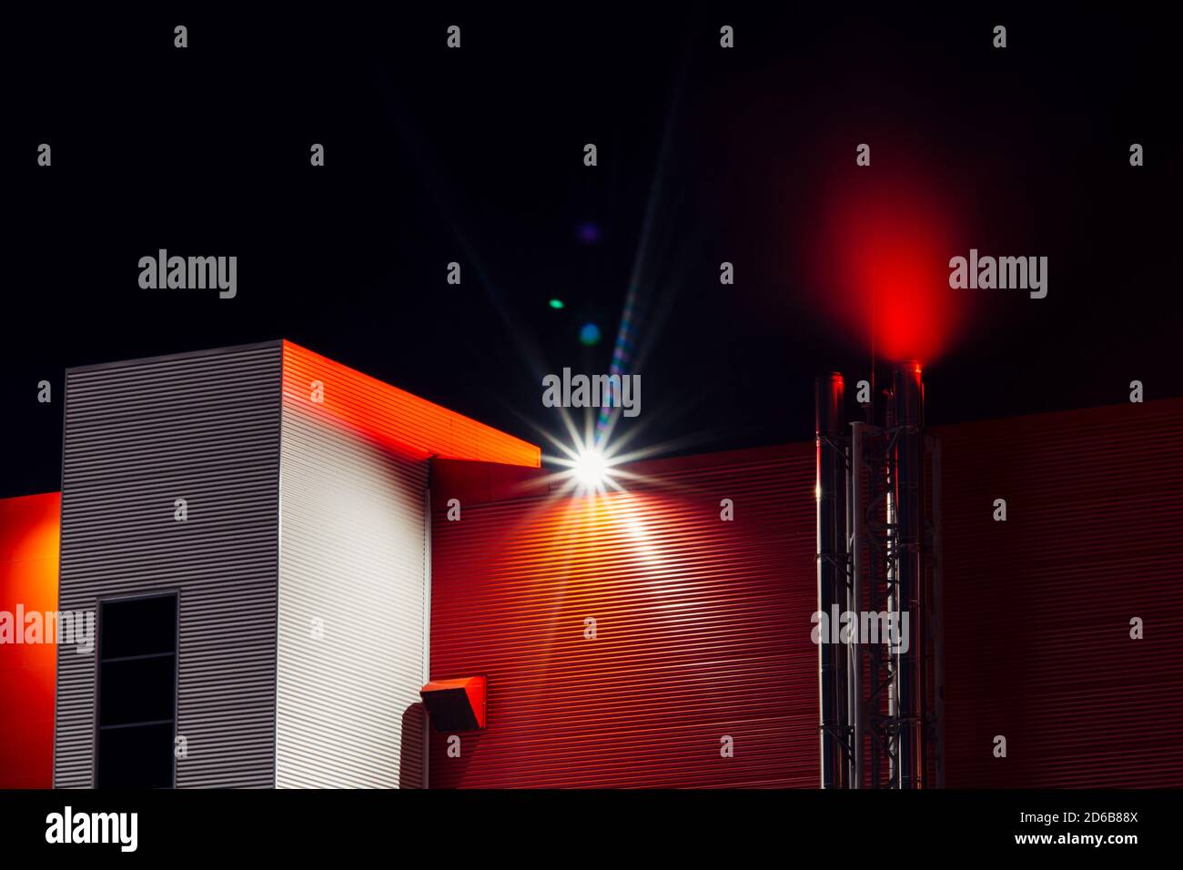 Red office building with smoke from pipe in night. Modern architecture ...