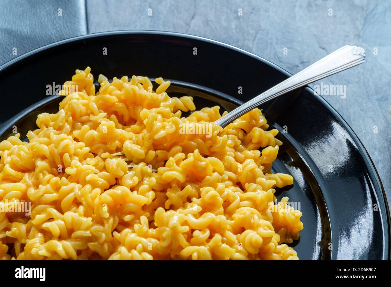 Delicious spiral macaroni and cheddar cheese on black plate Stock Photo ...