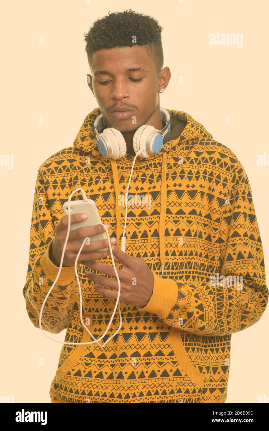 Young handsome African man using mobile phone while wearing headphones ...
