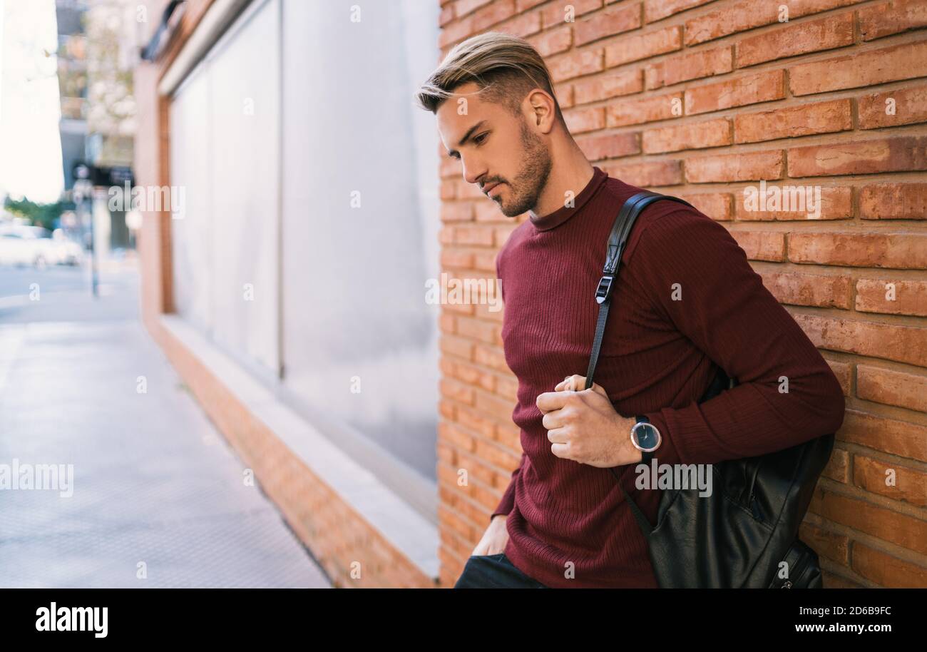 Portrait of young handsome man carrying a backpack and wearing casual ...