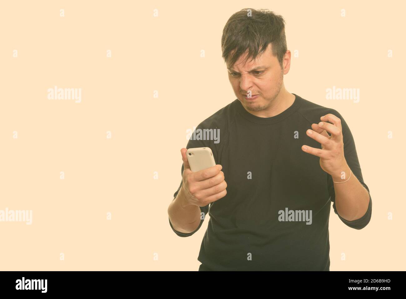 Studio shot of angry man holding mobile phone Stock Photo - Alamy