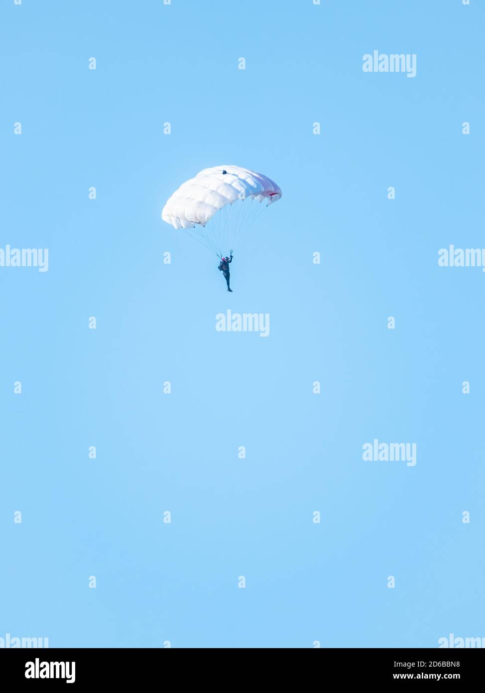 One parachutist with white parachute floats slowly at low altitude on ...